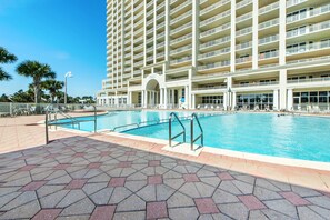 Um hotel grande com piscina, várias varandas e um caminho pavimentado.