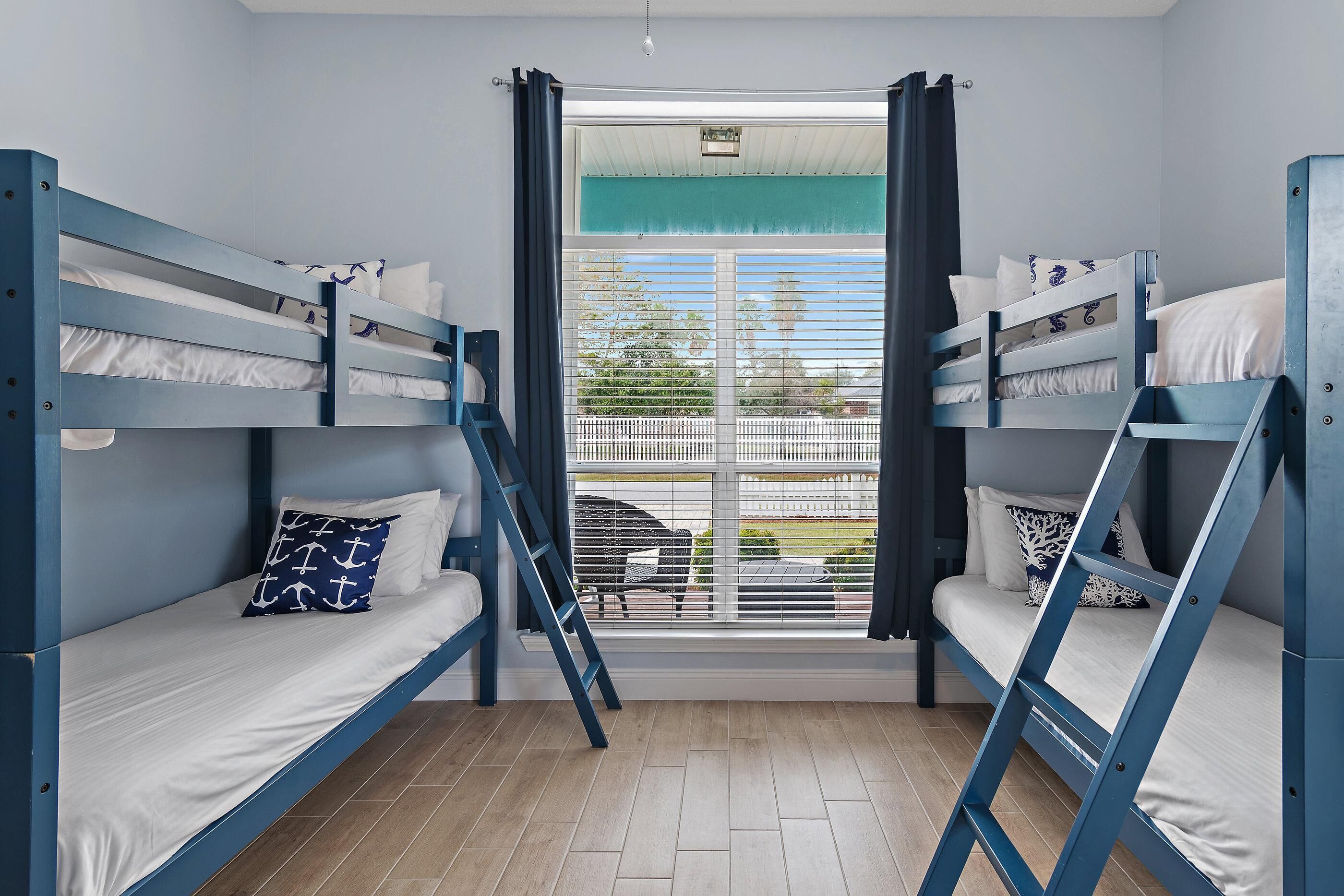 Quarto com duas beliches, uma janela com cortinas e vista para o exterior.