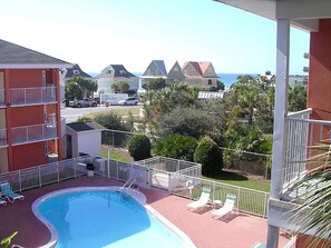 Uma área de piscina com espreguiçadeiras e vista para o oceano.