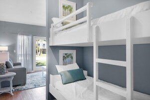 Quarto com beliche, parede cinza, quadro emoldurado e sofá cinza.