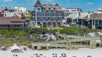 Um hotel à beira-mar com uma torre imponente, um calçadão que leva à praia e guarda-sóis de praia.