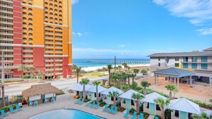 Um resort com piscina, vista para a praia e um píer ao fundo.