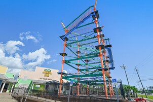 Um parque de aventura ao ar livre com uma estrutura de escalada e um edifício com a inscrição 'Adventure Zone'.