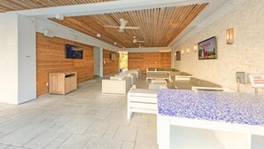Uma área de piscina interior moderna, com ripas de madeira no teto, assentos ao longo das paredes e uma placa indicando que a piscina está fechada.