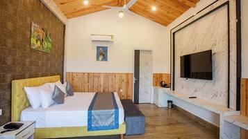 Quarto com cama, televisão, banco e porta.