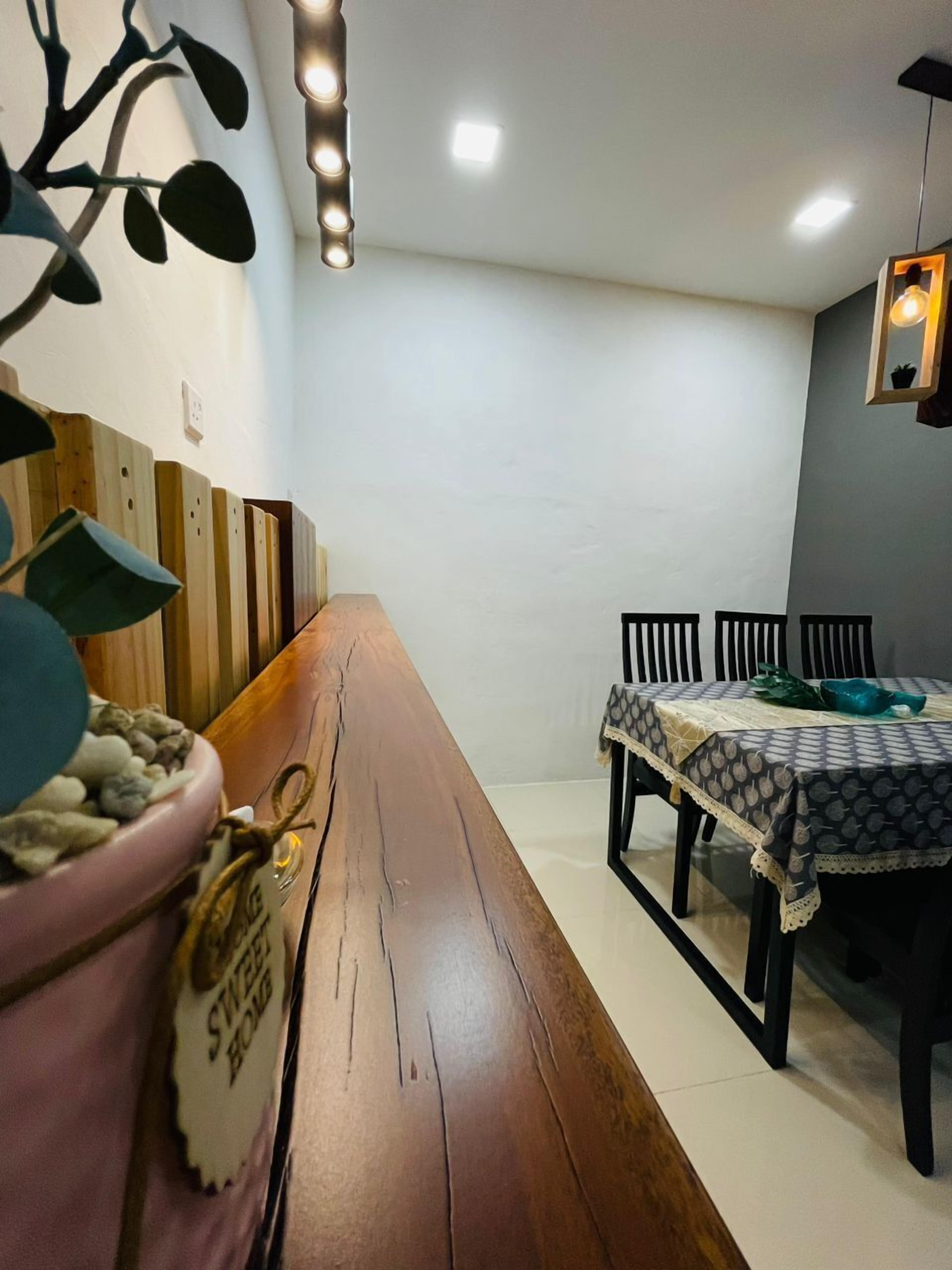 Uma área de refeições com um banco de madeira, uma mesa com toalha estampada e cadeiras.