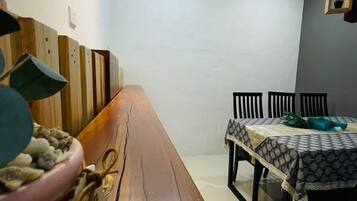 Uma área de refeições com um banco de madeira, uma mesa com toalha estampada e cadeiras.