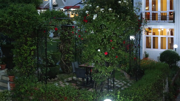 Um edifício de dois andares com várias varandas e um jardim bem iluminado.