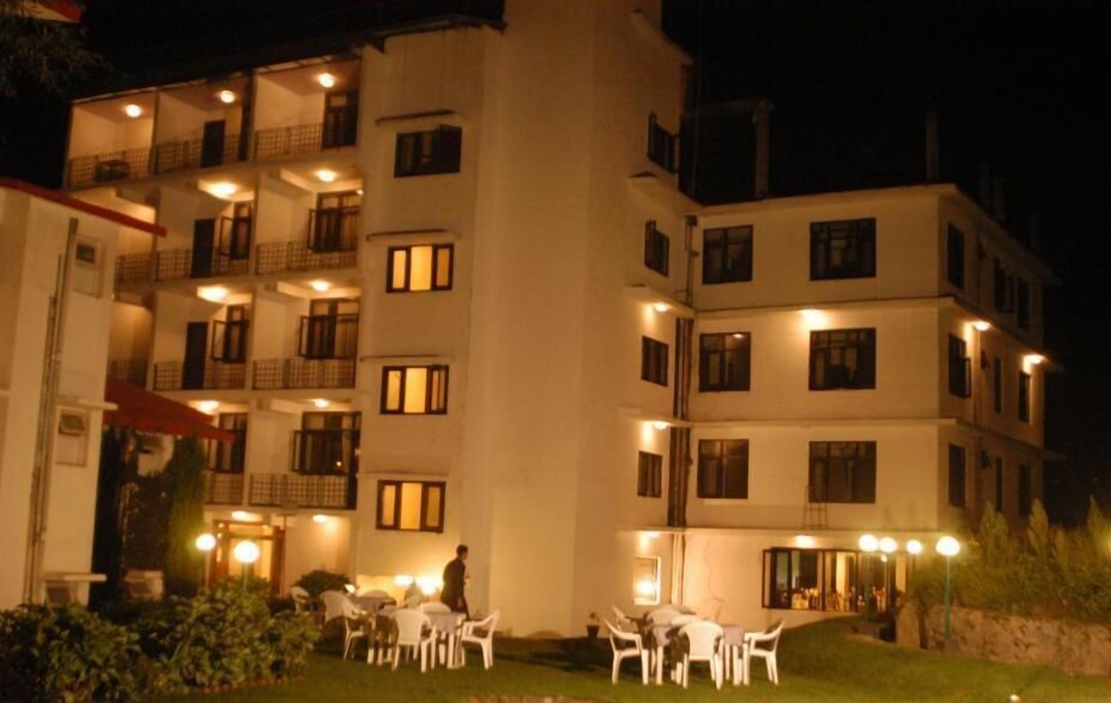 Um hotel com vários andares, varandas, área de estar externa e janelas iluminadas.