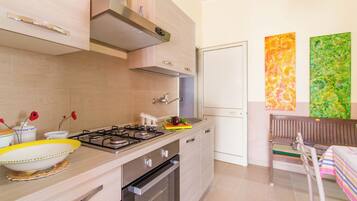 Uma cozinha moderna com fogão a gás, forno e um espaço de refeições com banco e mesa.