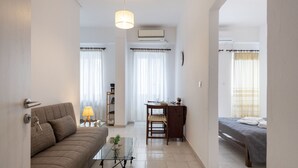 Quarto de hotel moderno com sofá, uma mesinha de centro com luminária, escrivaninha e cama.