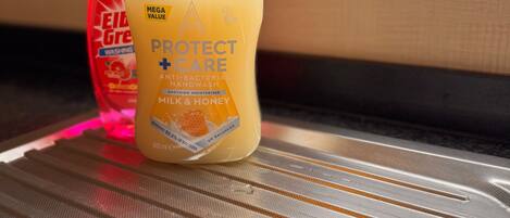 Um frasco de sabonete líquido 'PROTECT + CARE' e um frasco de sabonete líquido 'Elderflower' em um peitoril de janela.