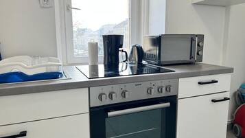 Uma cozinha moderna com forno embutido, micro-ondas e chaleira sobre a bancada.