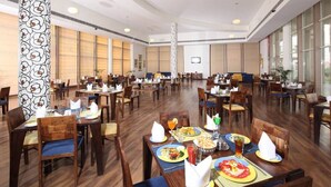Uma ampla sala de jantar com várias mesas e cadeiras, grandes janelas e um design de interiores moderno.