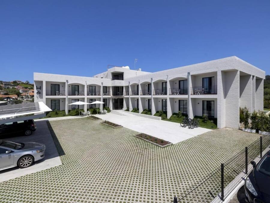 Um edifício moderno com várias varandas, área de estar coberta ao ar livre e estacionamento.