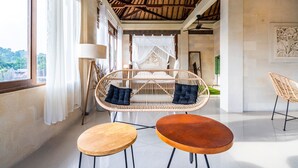 Um quarto espaçoso com uma cama grande, duas mesas de madeira redondas e cadeiras de vime.