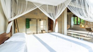 Um quarto espaçoso com uma cama grande, divisória de vidro e vista para um jardim exuberante.