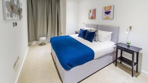 Quarto moderno com cama grande, mesa de cabeceira e obras de arte nas paredes.