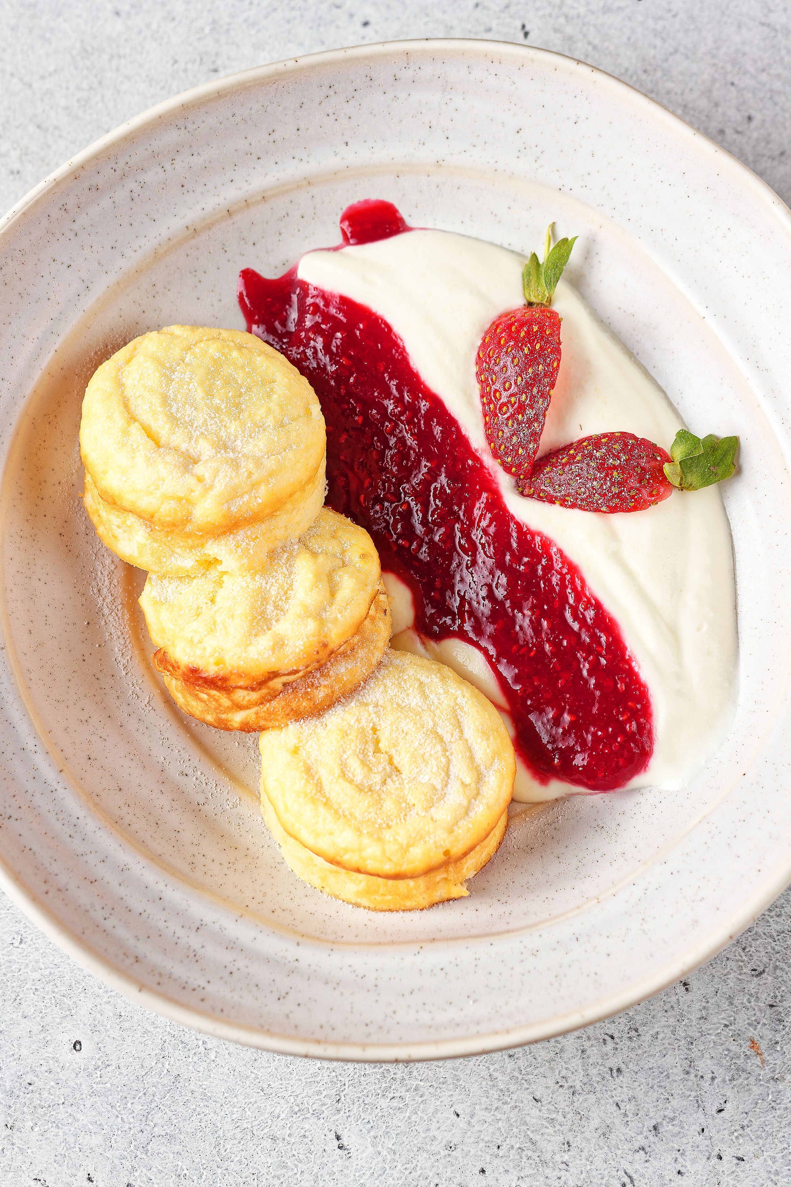 Um prato com panquecas, chantilly e compota de frutos vermelhos.
