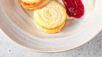 Um prato com panquecas, chantilly e compota de frutos vermelhos.