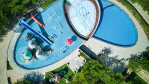 Vista aérea de um complexo de piscinas com várias piscinas e toboáguas, cercado por vegetação.