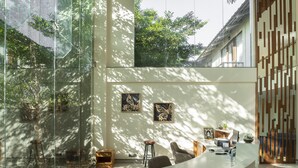 Uma área de recepção moderna com um balcão curvo, grandes janelas de vidro e um candelabro.