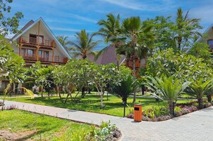 Resort com vários edifícios, um caminho pavimentado e vegetação exuberante, incluindo palmeiras.