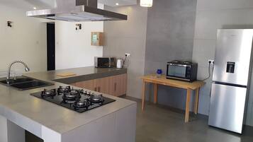Cozinha moderna com fogão a gás, eletrodomésticos de aço inoxidável, micro-ondas e geladeira.