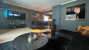 Uma sala de estar moderna com televisão de tela plana, lareira e área de jantar com cadeiras e mesa.