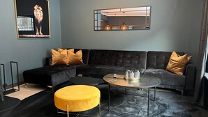 Uma sala de estar moderna com um sofá seccional, uma mesa de centro redonda e um banquinho amarelo.