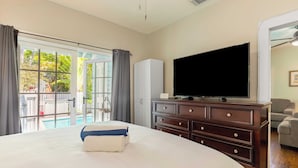 Quarto de hotel com cama grande, televisão de tela plana, cômoda e vista para a piscina e área externa.