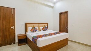 Quarto com cama de madeira, mesa de cabeceira e duas portas de madeira.