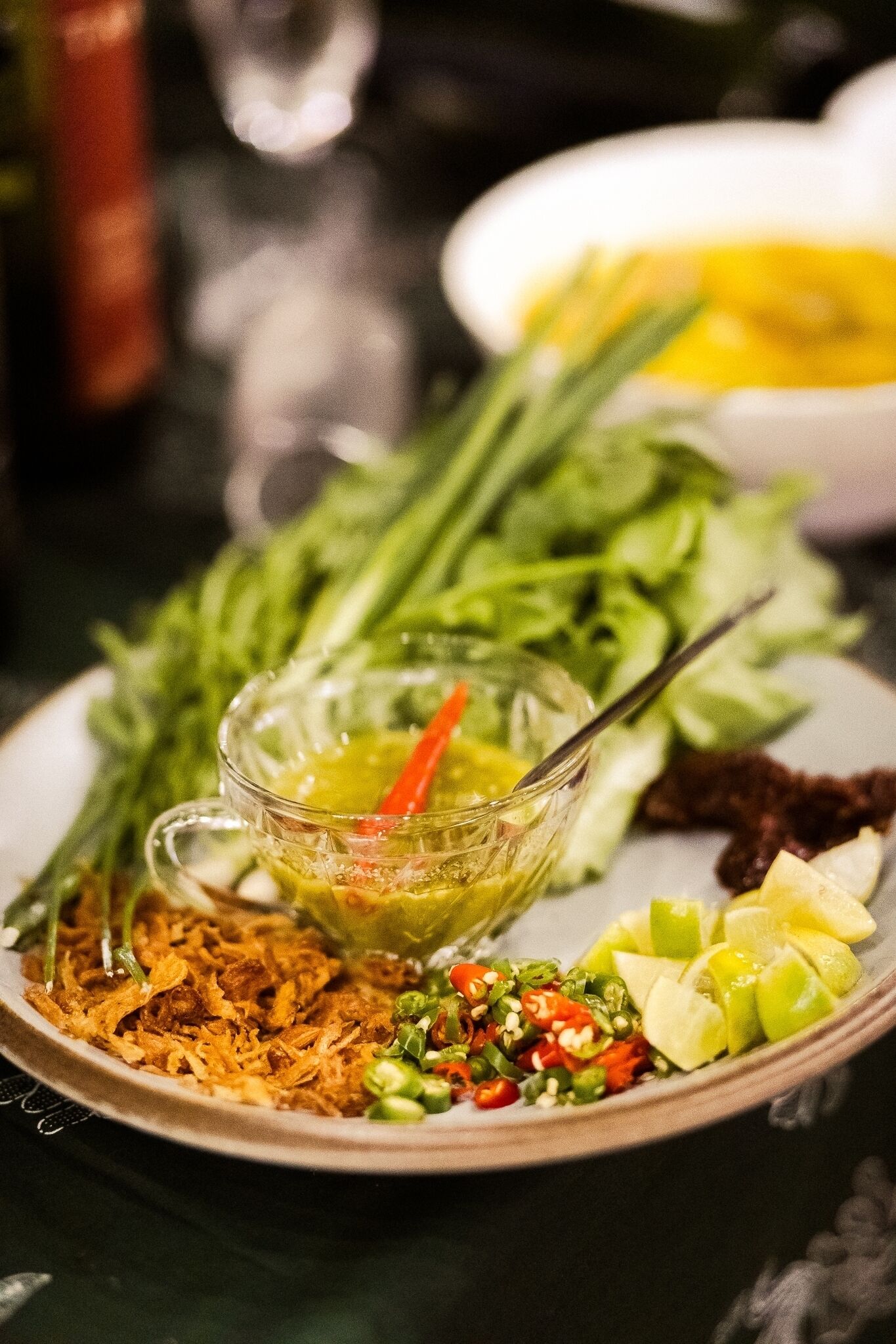 Um prato com diversos alimentos, incluindo carne desfiada, vegetais frescos e uma pequena tigela de molho.