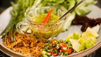 Um prato com diversos alimentos, incluindo carne desfiada, vegetais frescos e uma pequena tigela de molho.
