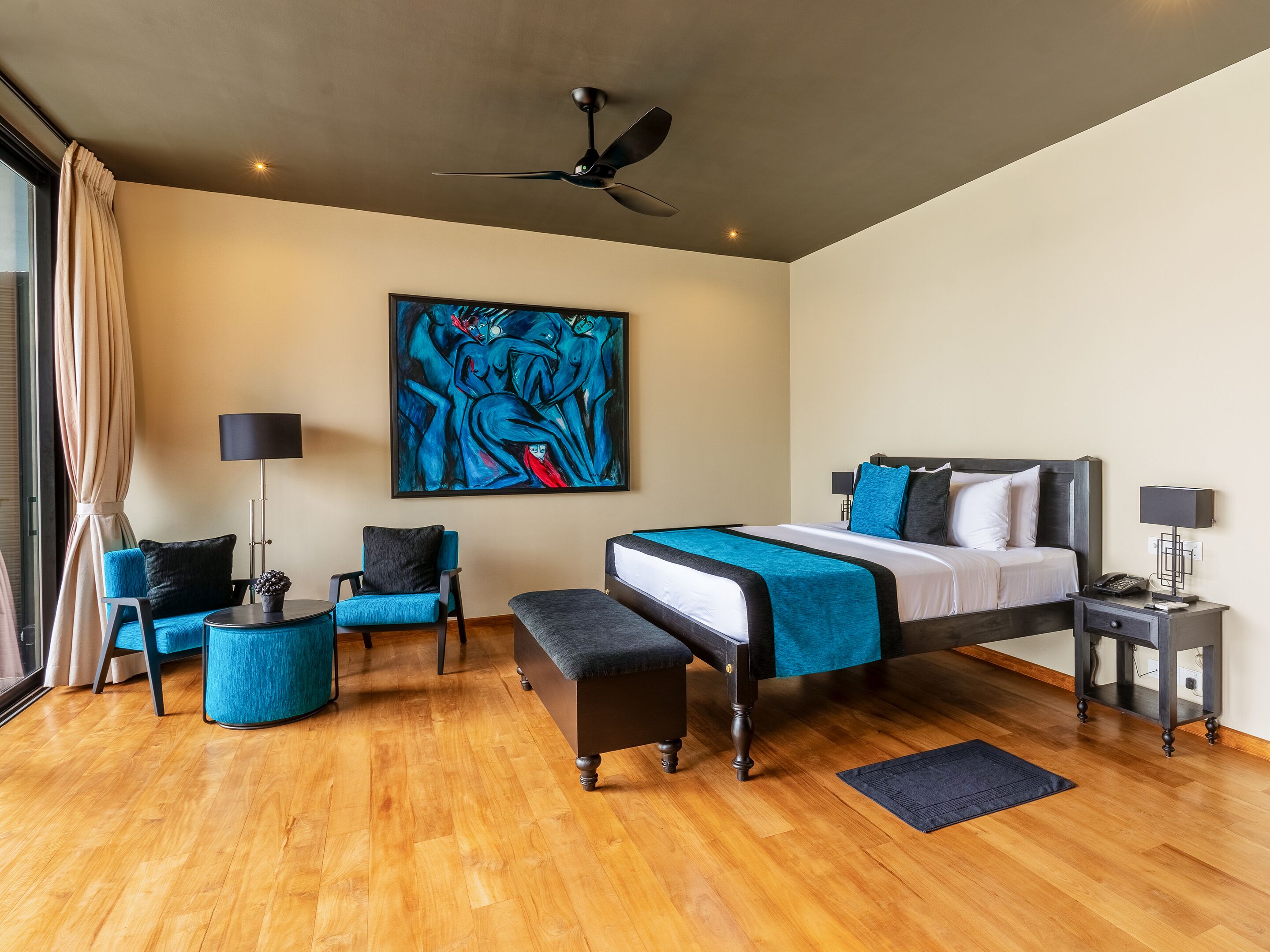 Quarto moderno com uma cama grande, um ventilador de teto, um quadro e vista para a cidade.