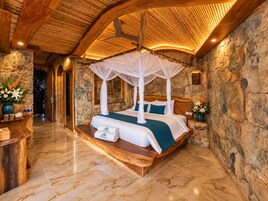 Um quarto amplo com parede de pedra, teto de madeira e cama com dossel.