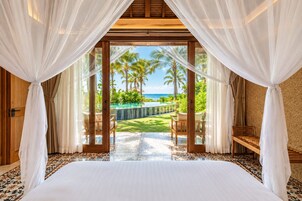Quarto com cama grande, vista para o oceano e piscina.
