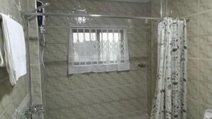 Casa de banho com chuveiro, sanita e lavatório.