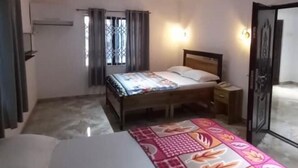 Quarto com cama, mesa de cabeceira, ventilador de teto e janela com cortinas.
