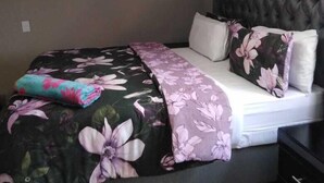 Um quarto com uma cama, uma mesa de cabeceira e um guarda-roupa.