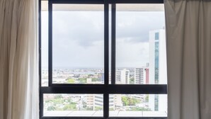 Janela com vista para um horizonte urbano, incluindo edifícios e áreas verdes.