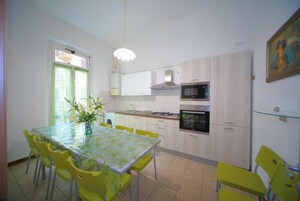 Cozinha moderna com área de refeições, incluindo uma mesa com cadeiras, micro-ondas, forno e pia.