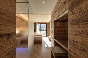 Um interior moderno com paredes de madeira, uma cama, um banco e vista para o exterior.