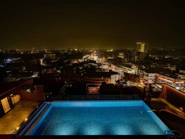 Piscina no terraço com vista para a cidade à noite.