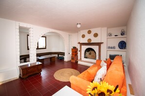 Uma sala de estar com lareira, sofá, mesa de centro e um armário de madeira.