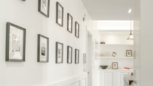 Um corredor com quadros nas paredes, uma porta branca e um armário branco ao fundo.