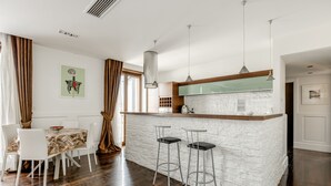Cozinha moderna com ilha de mármore branco, dois banquetas e iluminação pendente.