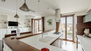 Cozinha moderna com ilha grande, armários brancos e iluminação pendente.