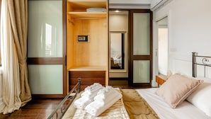 Quarto de hotel com cama, guarda-roupa de madeira, casa de banho com chuveiro e vista para a cidade.