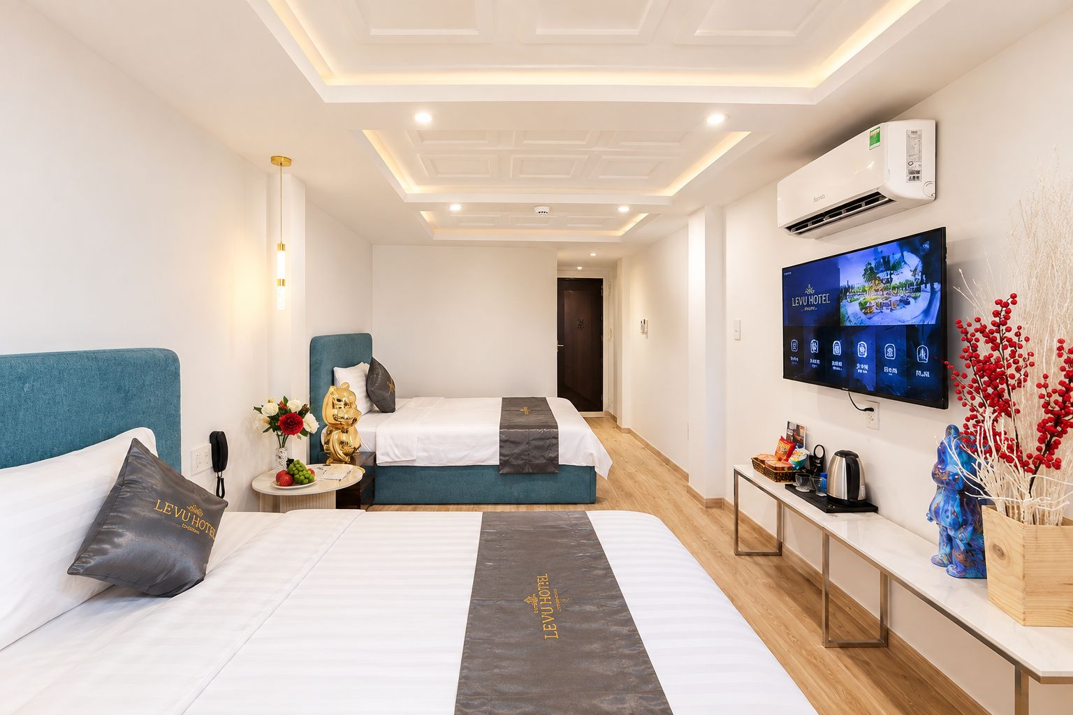 Quarto de hotel com duas camas, televisão, escrivaninha e um vaso decorativo.